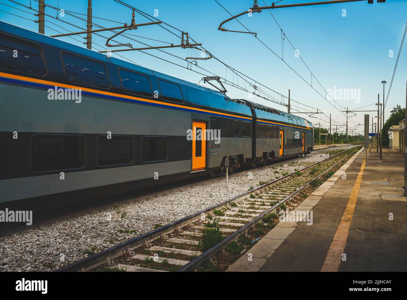 Double decker train passing by the train station in Italy Stock Photo ...