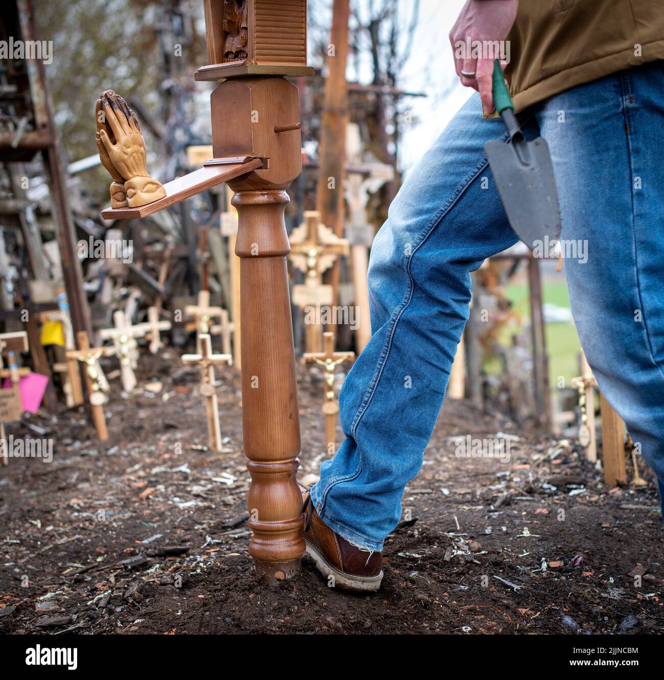 The lower body of a male holding a trowel standing net to a wooden ...