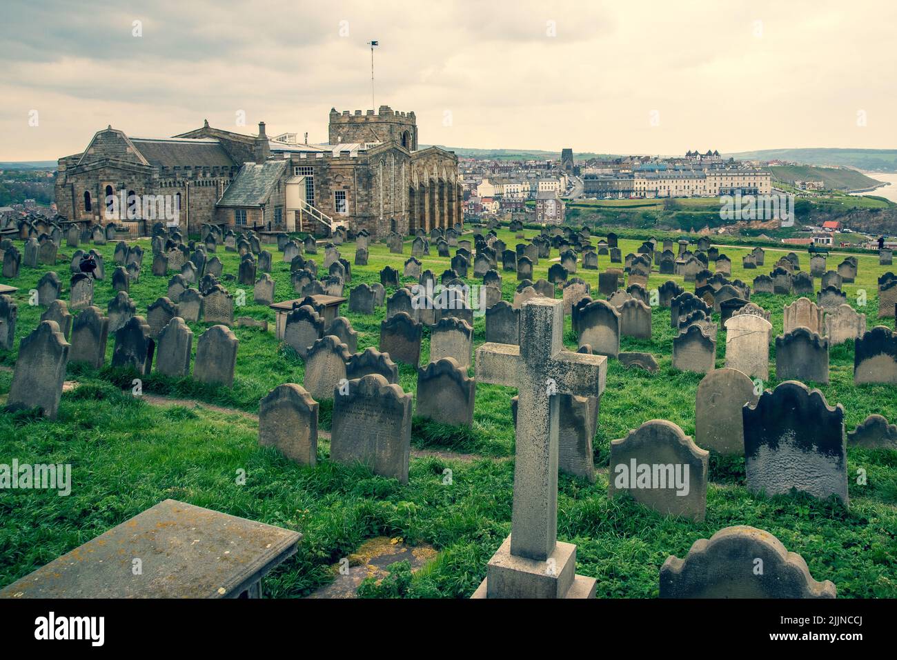 A graveyard with tombstones and green grass with a church in the ...