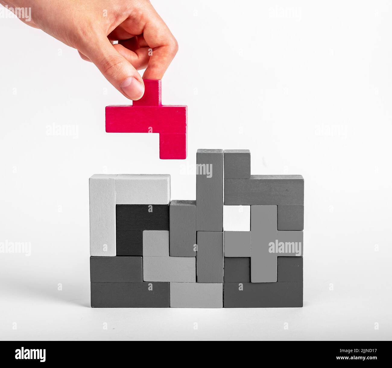 Hand putting outstanding red element in tetris puzzle construction ...