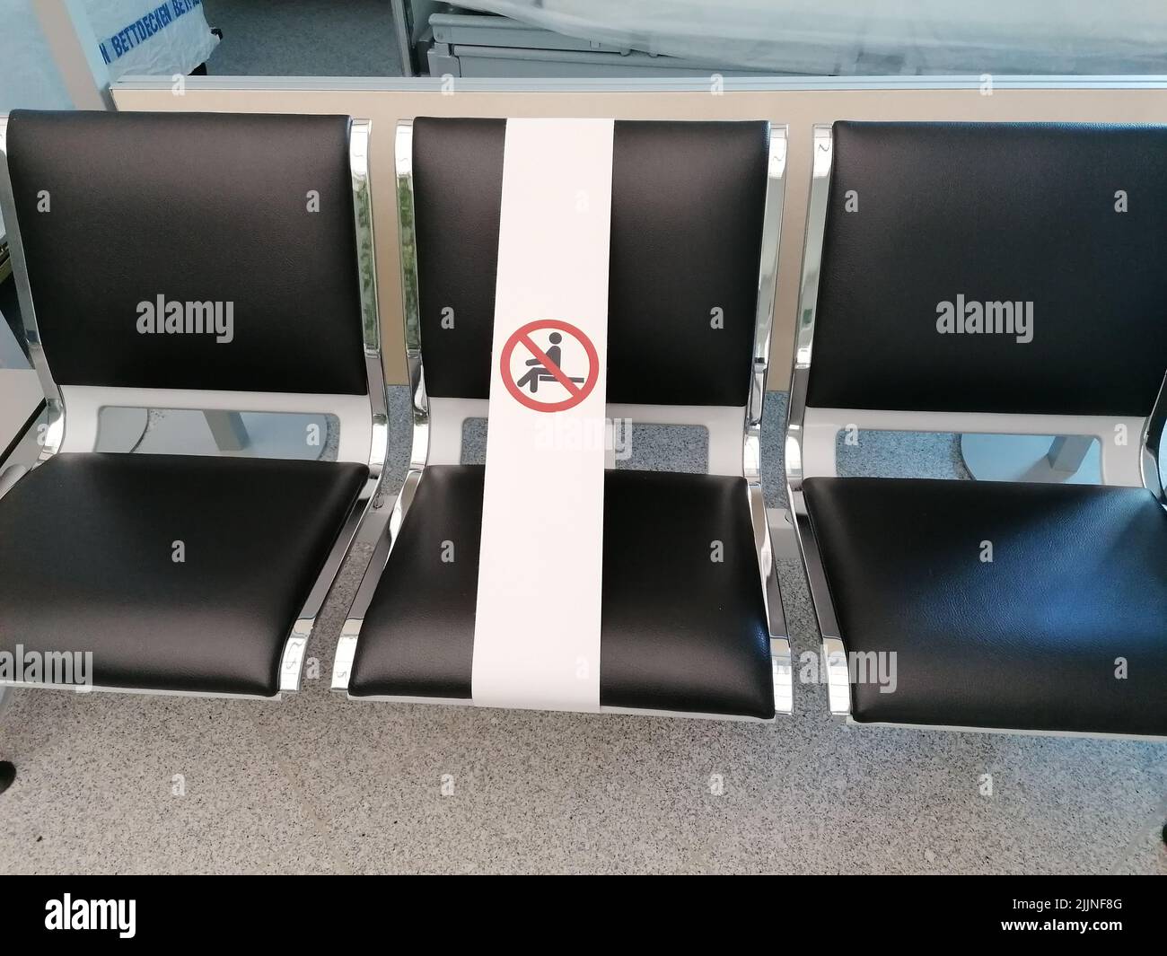 A row of waiting hall chairs with a restriction sign for keeping social ...
