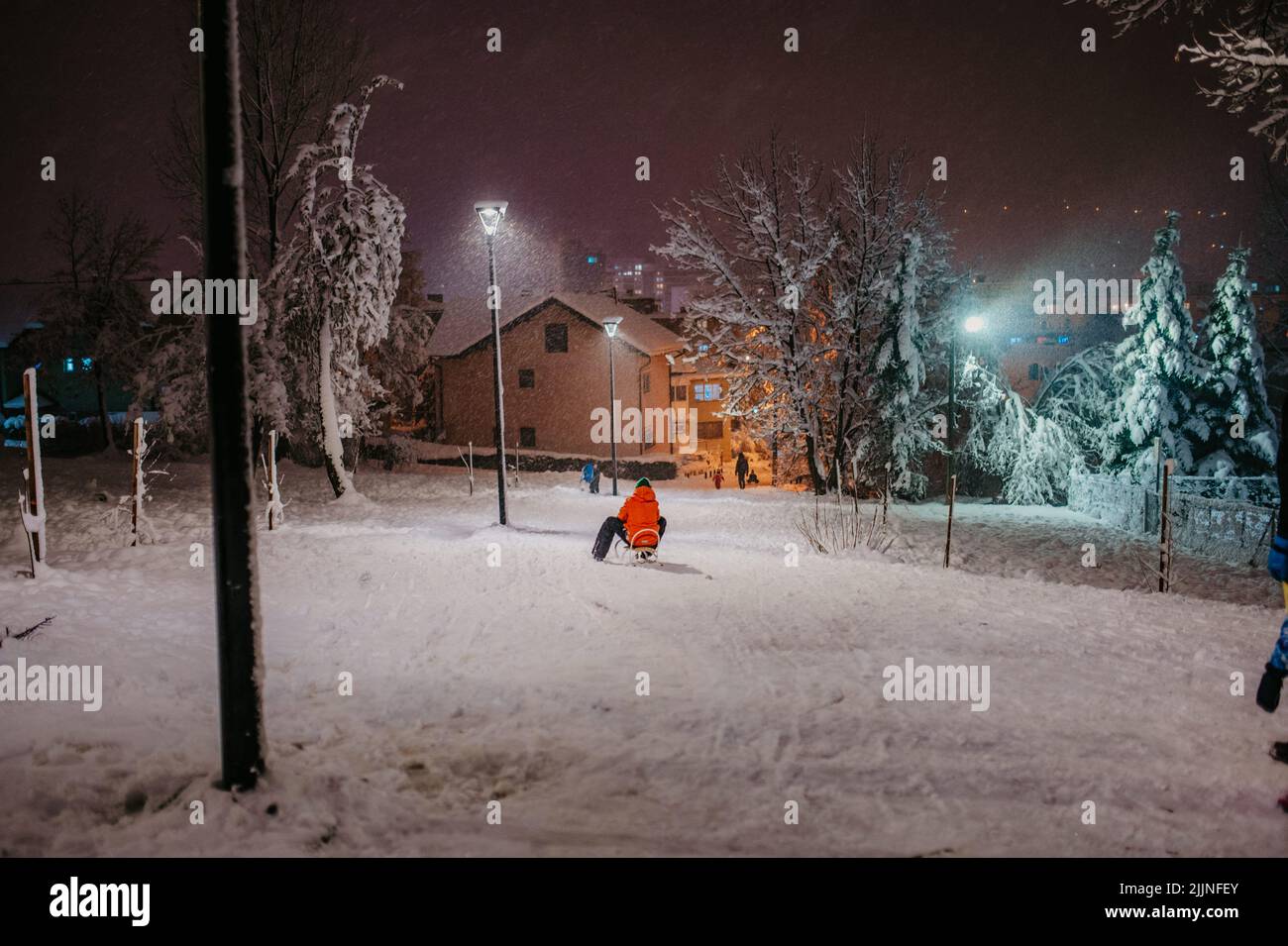 A distant view of kids playing in the garden covered in snow during ...