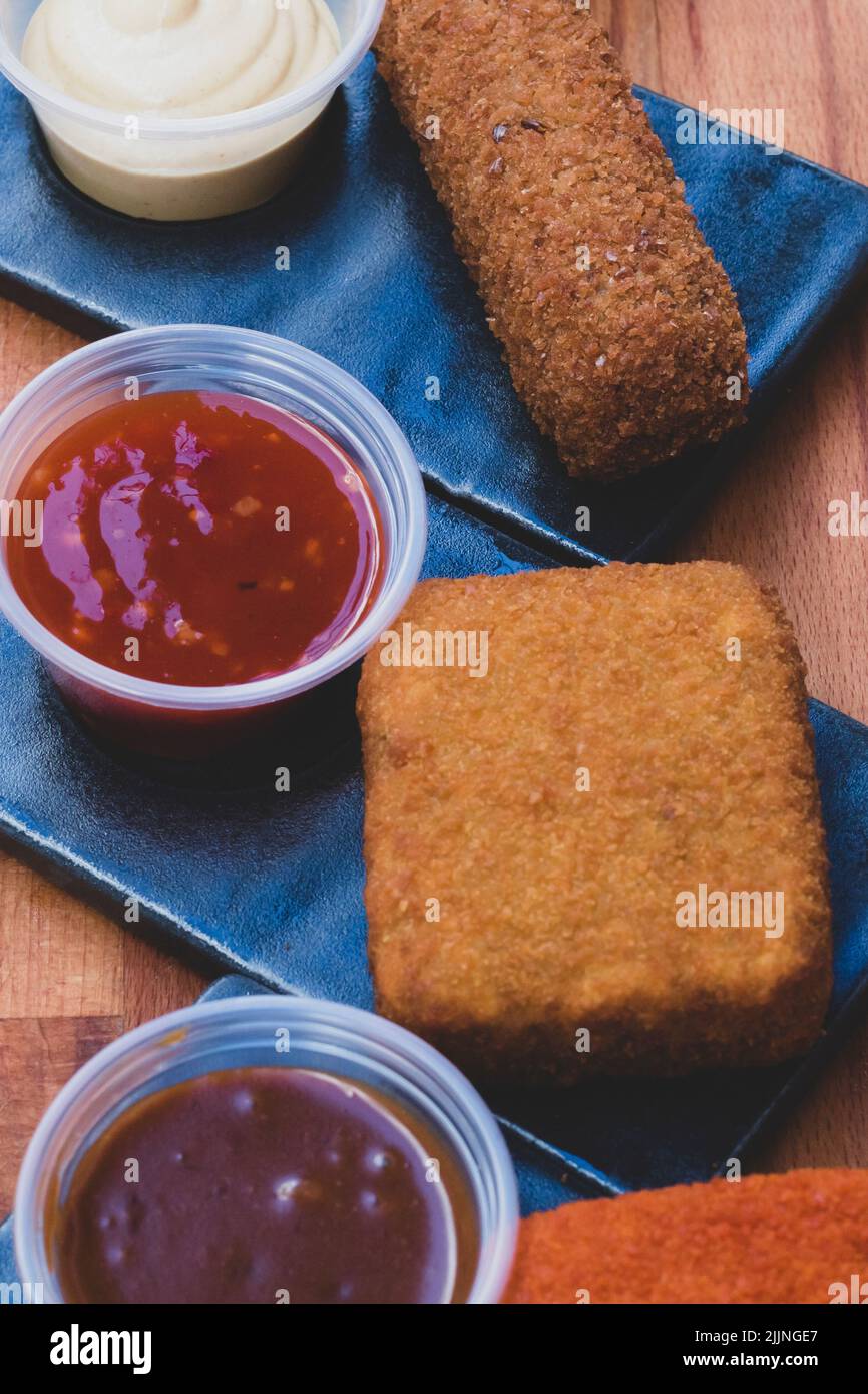 A vertical shot of different types of deep fried nuggets with sauces ...