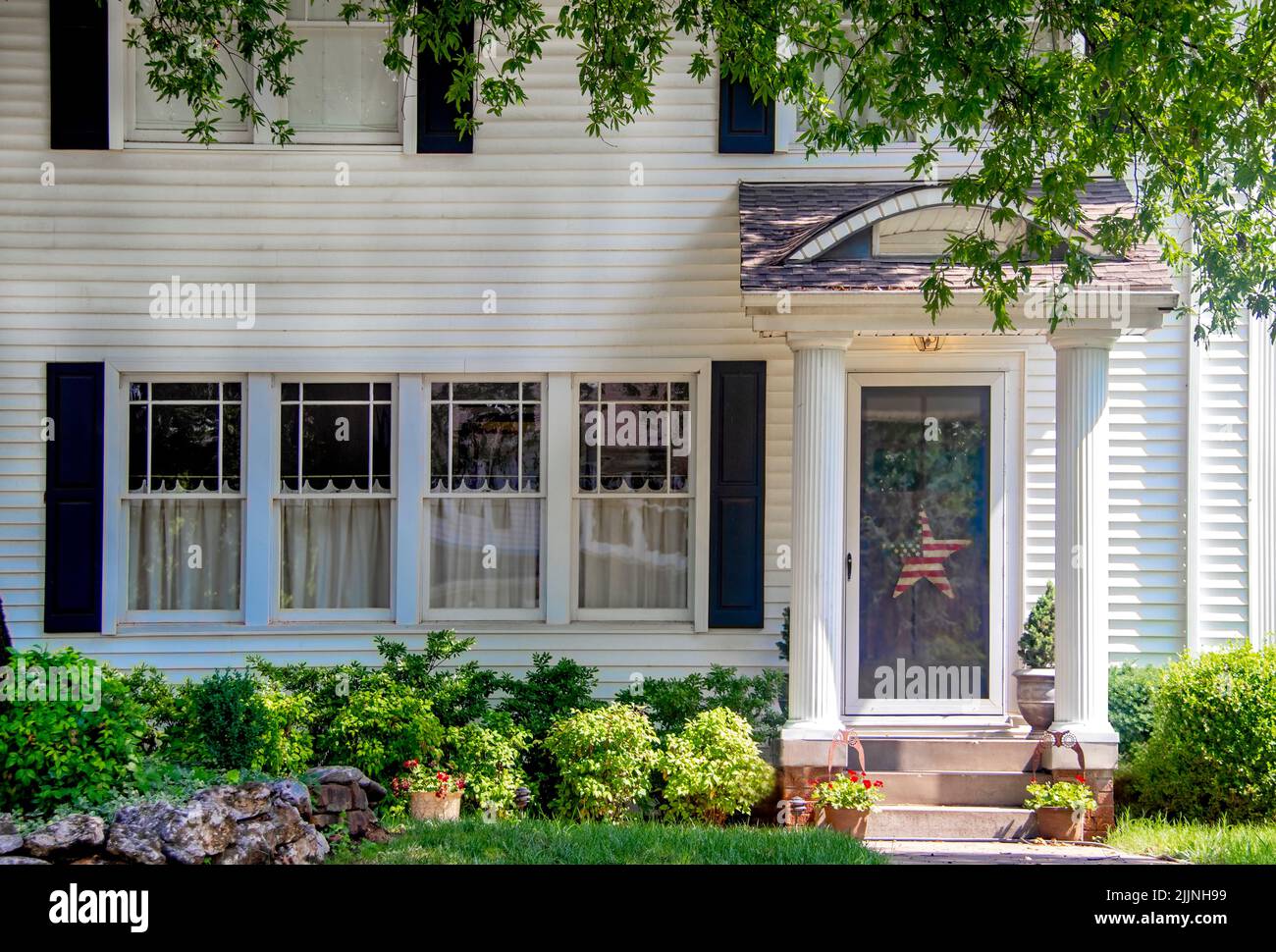 Entrance of charming white wood house with columns on porch and ...