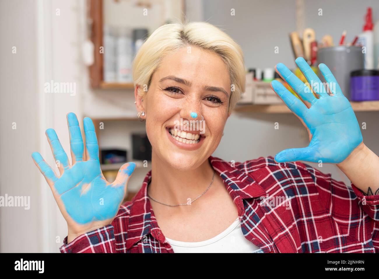 A beautiful Hispanic blonde female artist working in her studio with ...