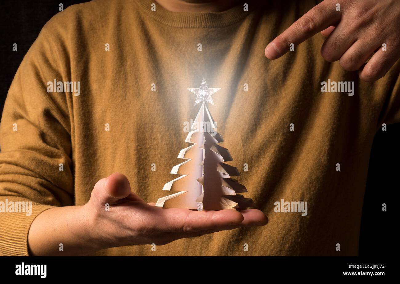 A scenic shot of a tree made of origami with a burning star in the hand ...
