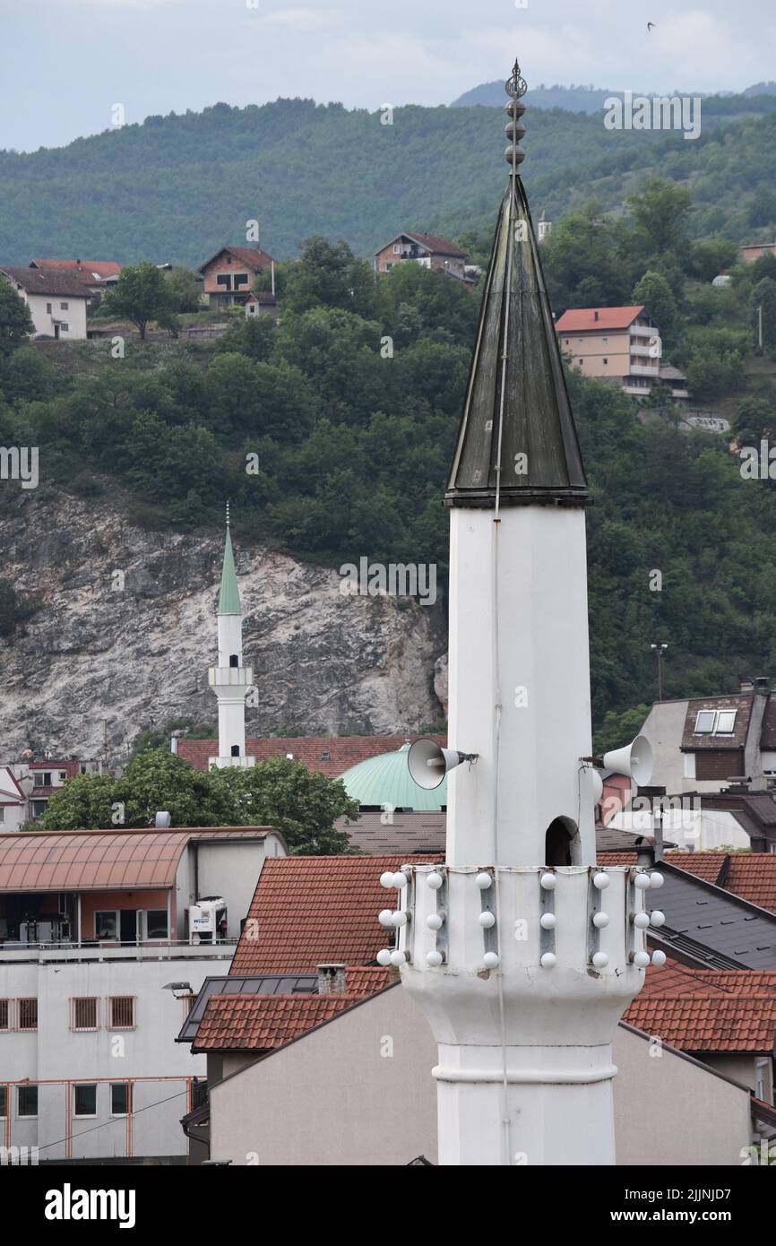 A vertical shot of a spire of a white building with other low buildings ...