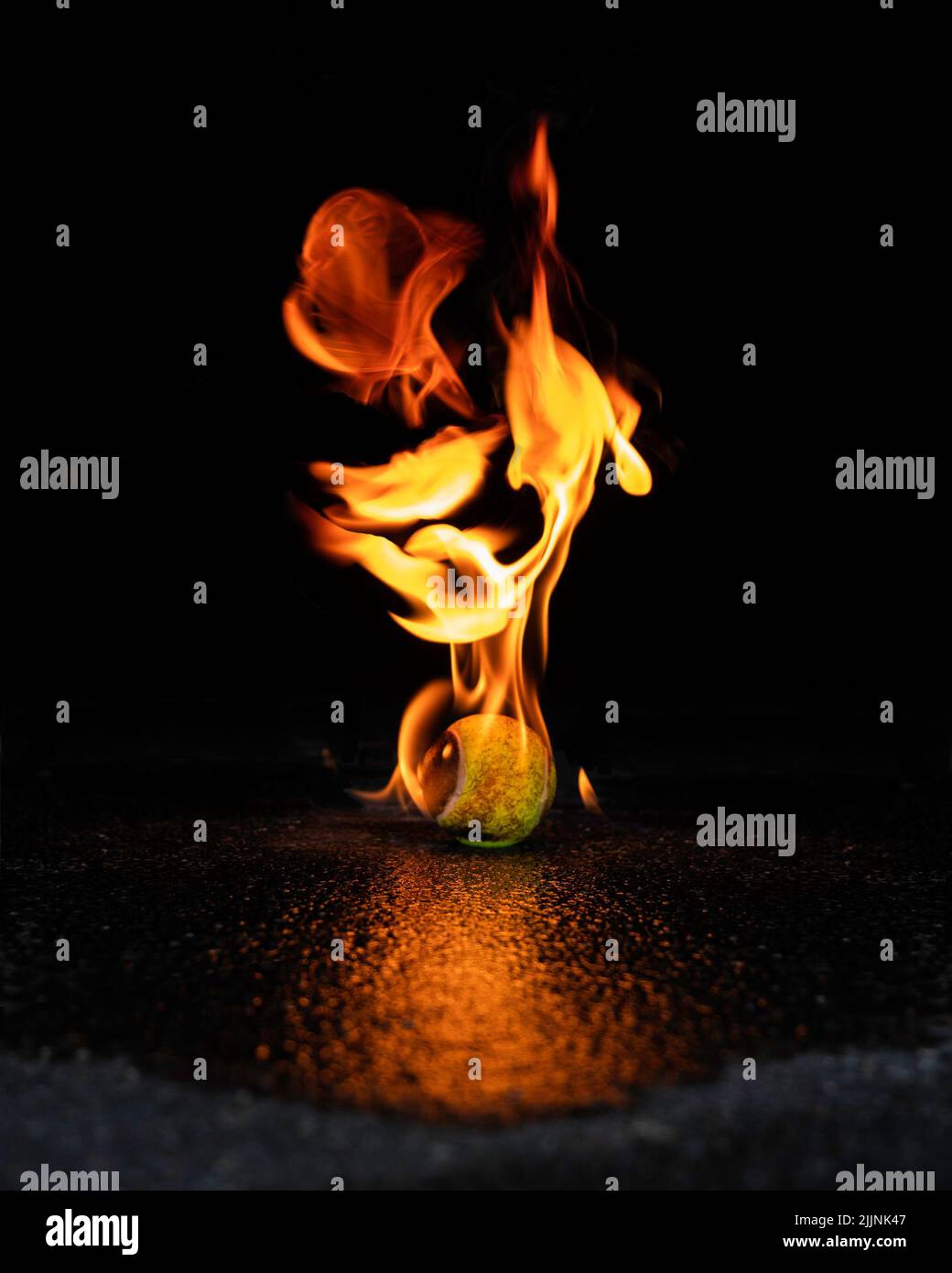 A vertical closeup shot of the burning tennis ball on the black ...