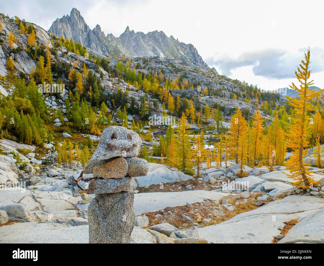 A hiking cairn with smiley face surrounded by golden Larches Stock ...