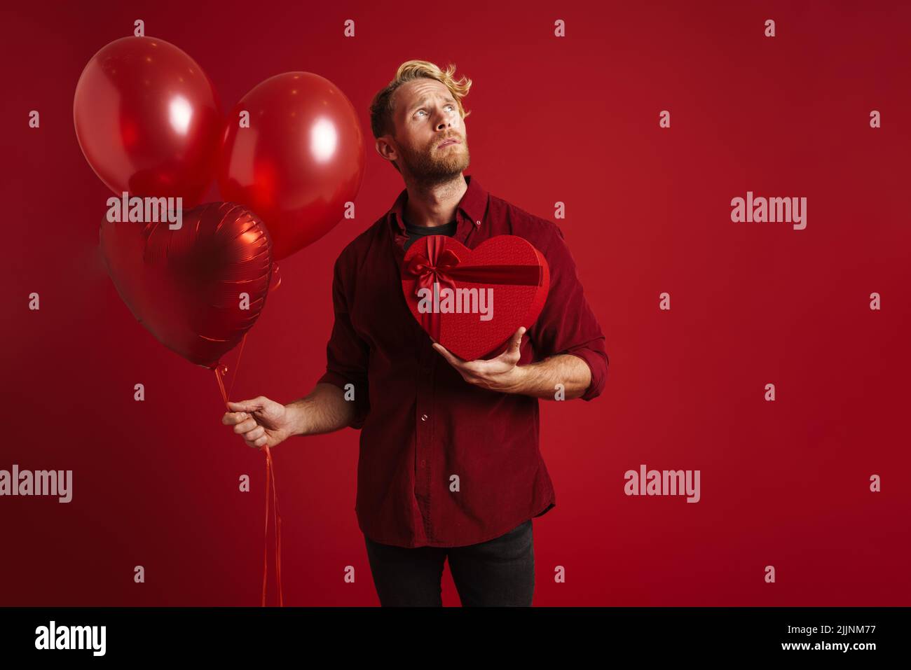 White bearded man posing with balloons and heart gift box isolated over ...
