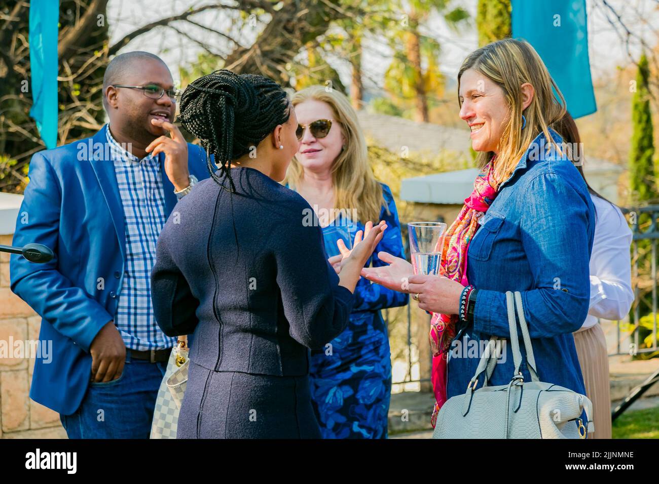 A group of multiracial VIP guests mingling at an outdoor social event ...
