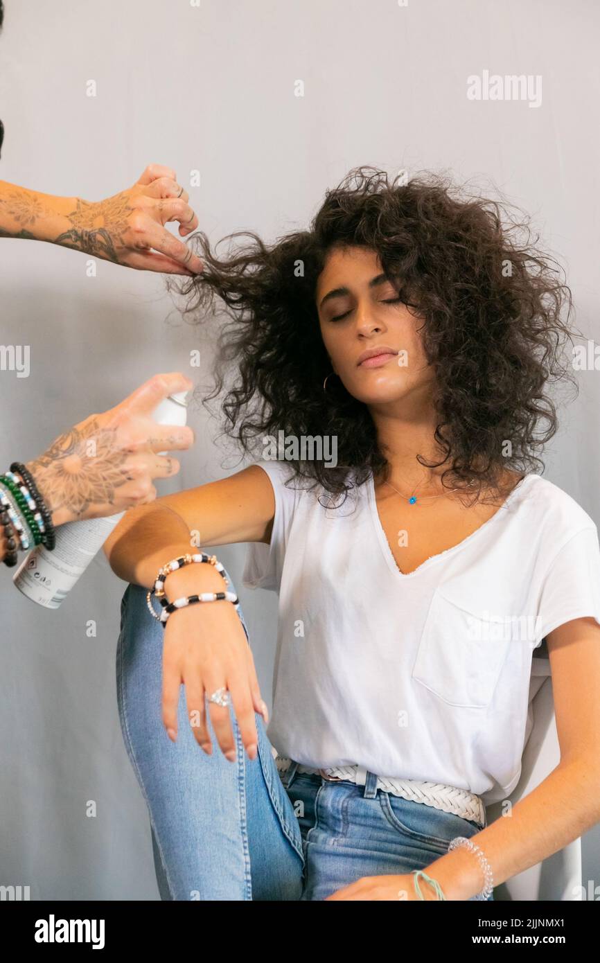 A vertical shot of a young black-haired female model getting her hair ...