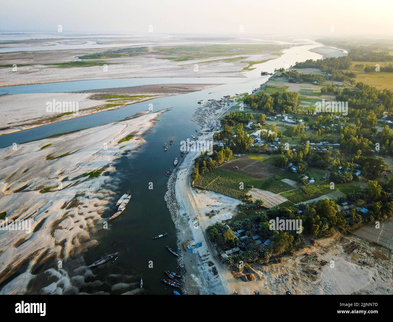 An aerial view of the flowing river surrounded by greens under the ...