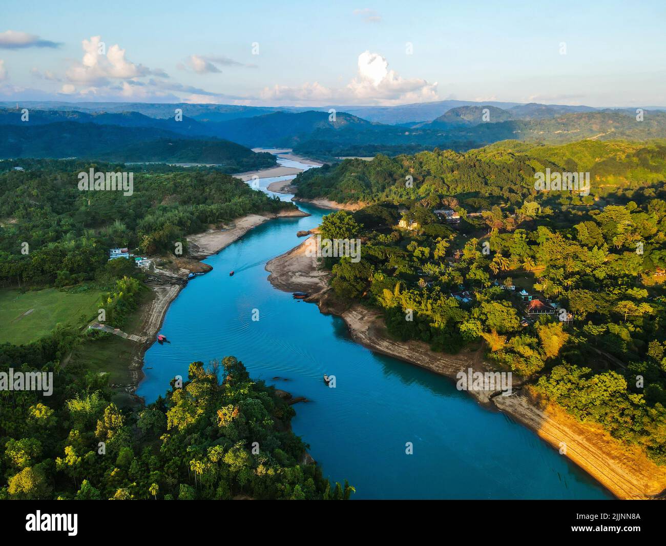 An aerial view of the flowing river surrounded by greens under the ...