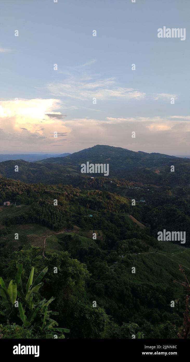An aerial view of the green mountains gleaming under the cloudy blue ...