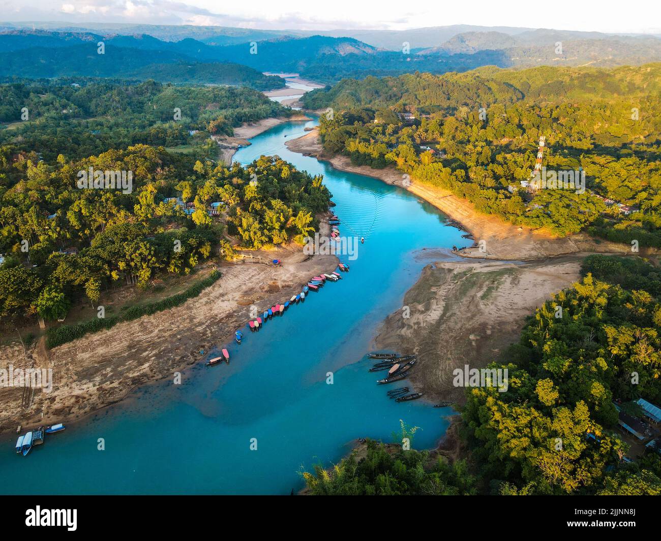 An aerial view of the flowing river surrounded by greens under the ...