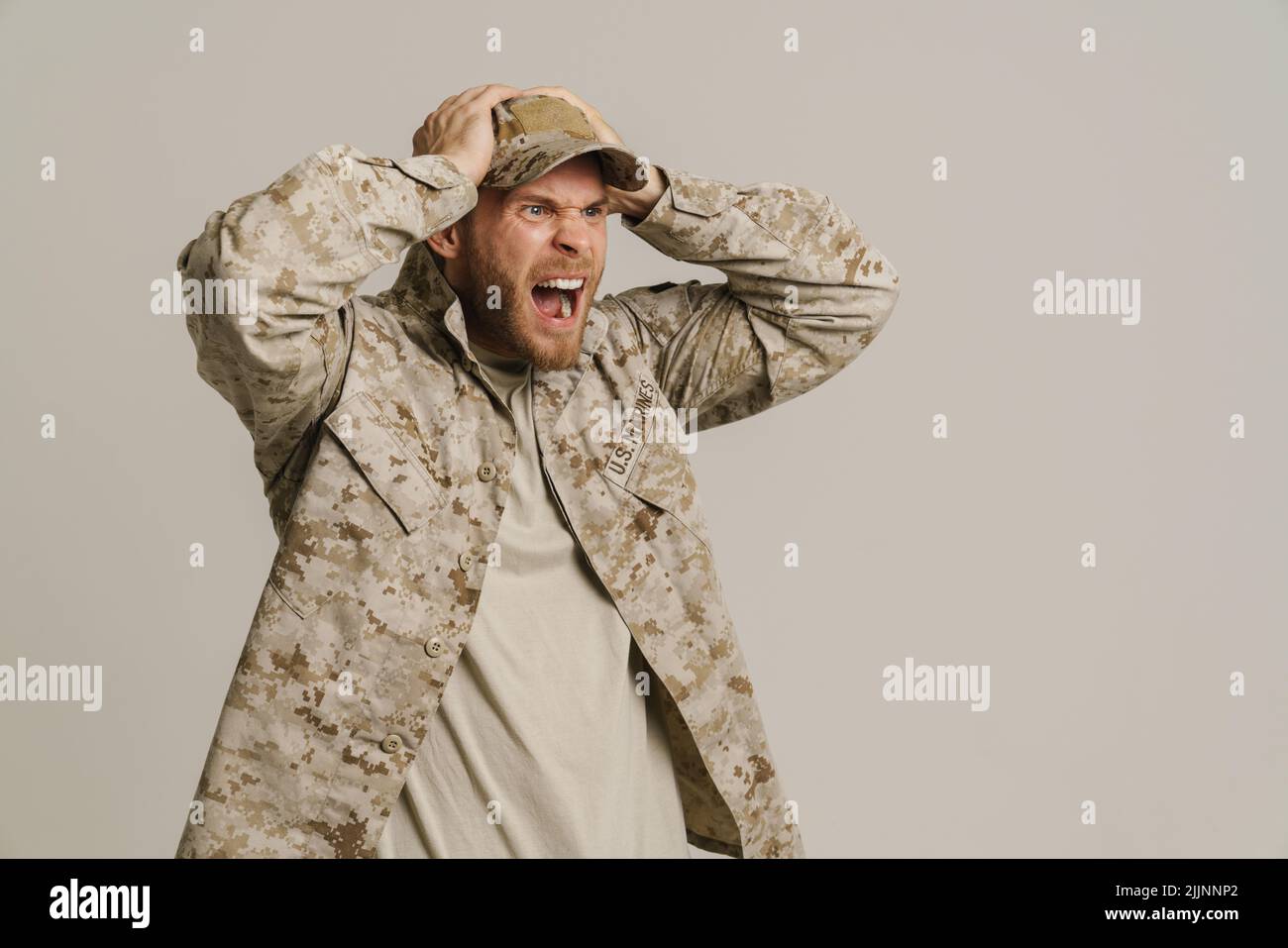 Furious military man wearing uniform holding head and screaming ...
