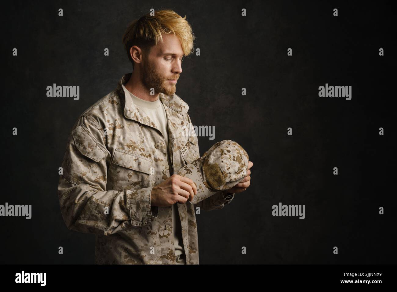 White military man wearing uniform posing with cap isolated over grey ...