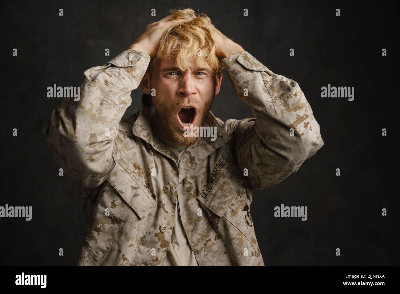 Unhappy military man with headache holding his head and screaming ...