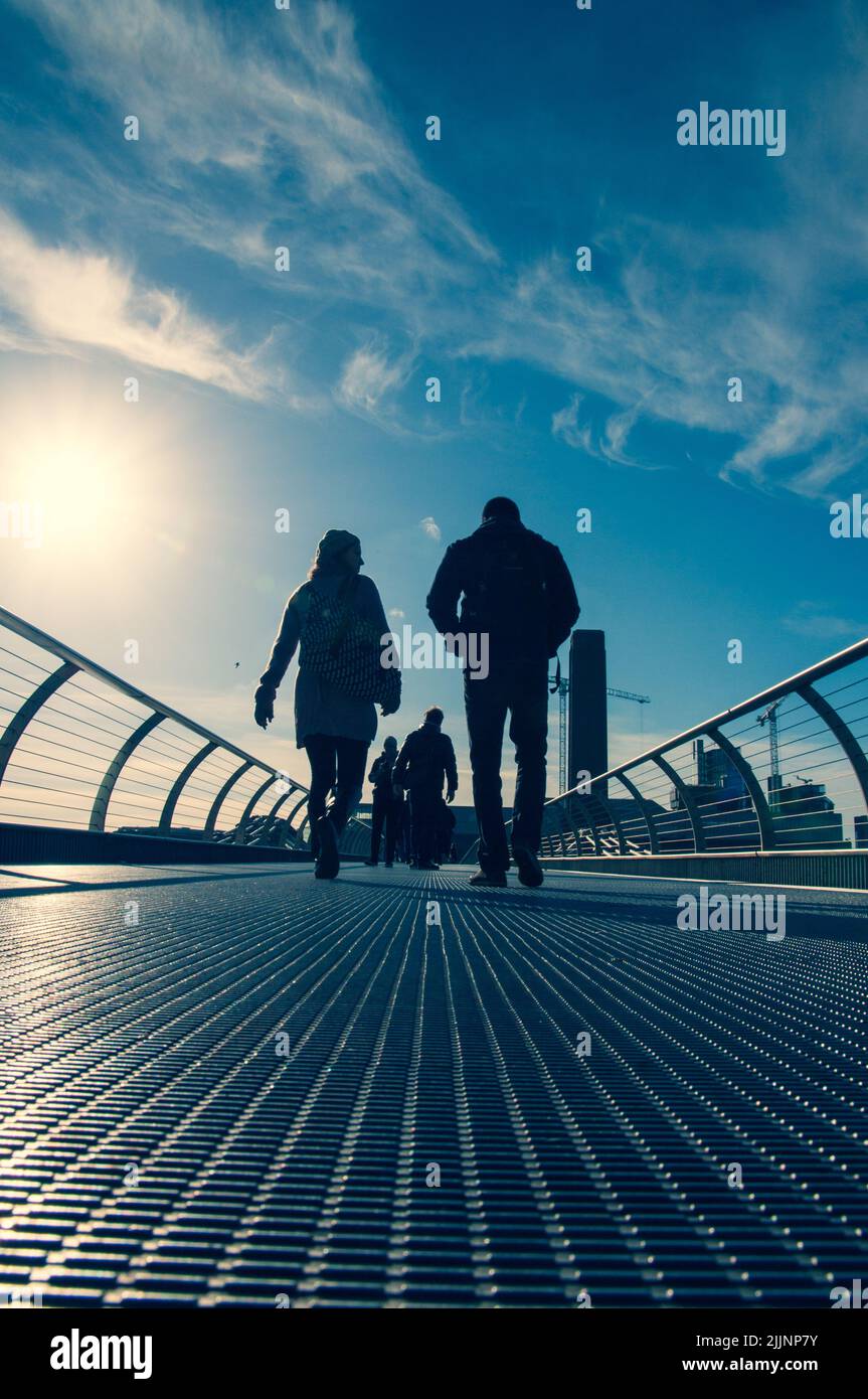 A vertical shot of peoples silhouettes walking on a bridge Stock Photo ...