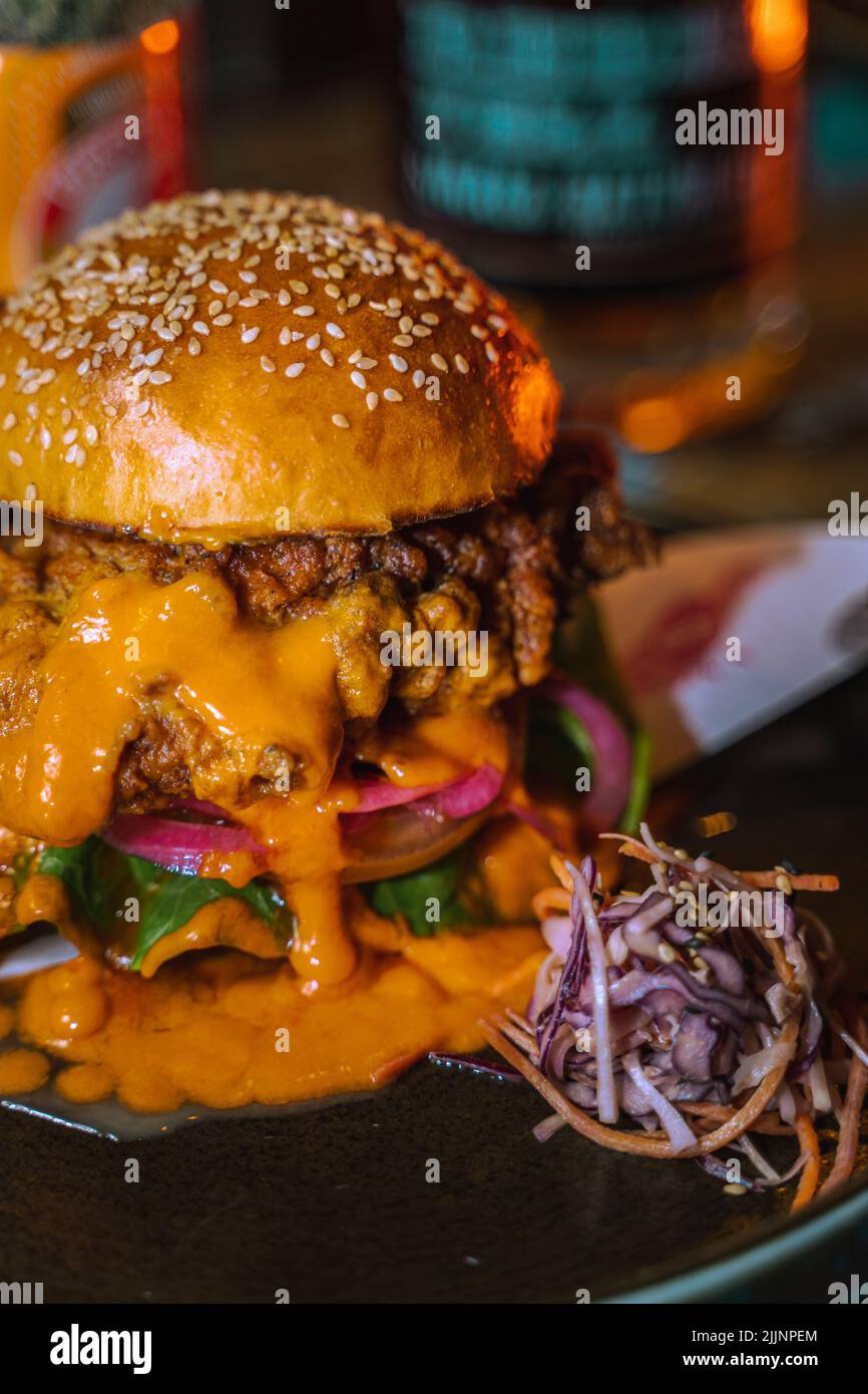 A vertical shot of a chicken burger in a dark grungy restaurant setting ...