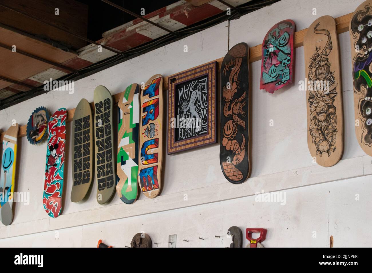 A row of skateboards with different designs on a wall Stock Photo - Alamy