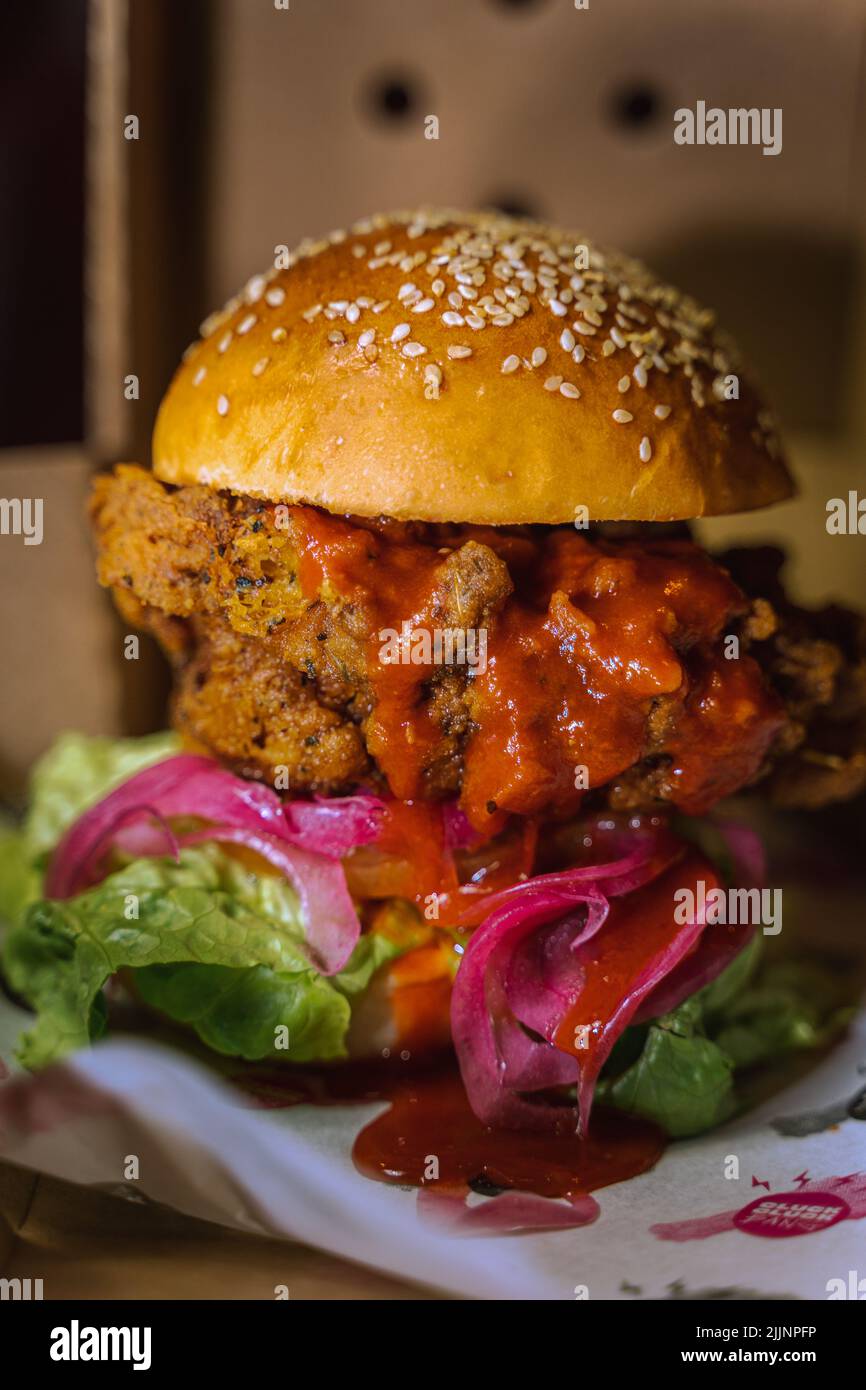 A vertical shot of a chicken burger in a dark grungy restaurant setting ...