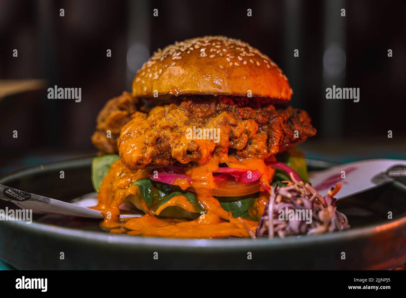 A closeup shot of chicken burger in a dark grungy restaurant setting ...