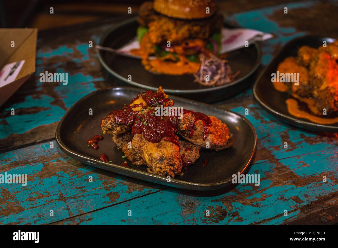 The chicken burger and wings in a dark grungy restaurant setting Stock ...