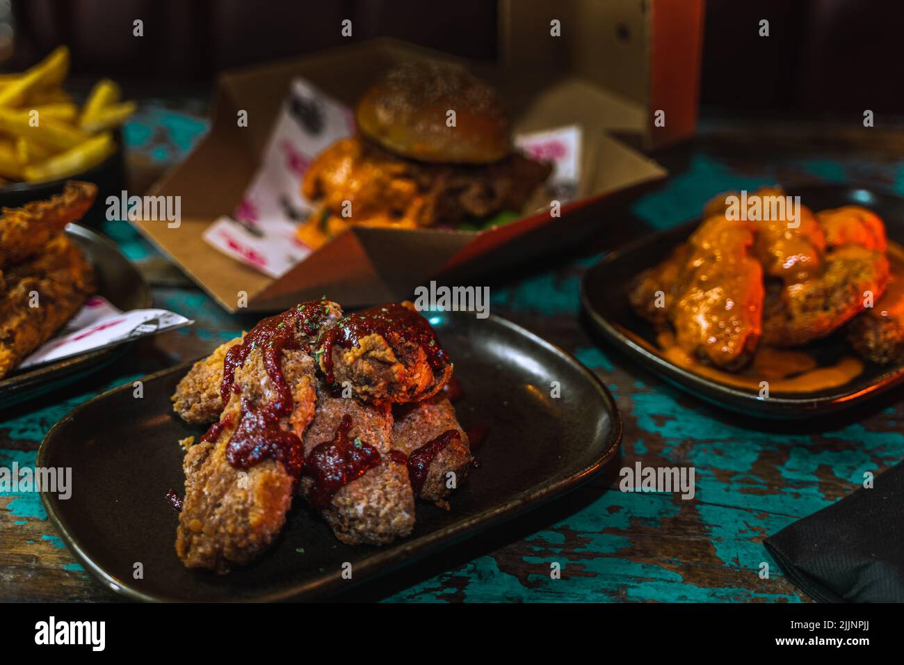 A closeup shot of chicken burgers and wings in dark grungy restaurant ...