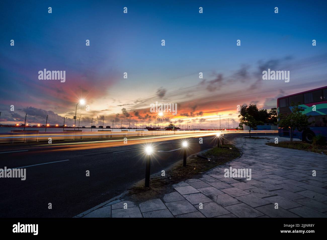 A beautiful sunset sky over a highway with passing car lights and ...