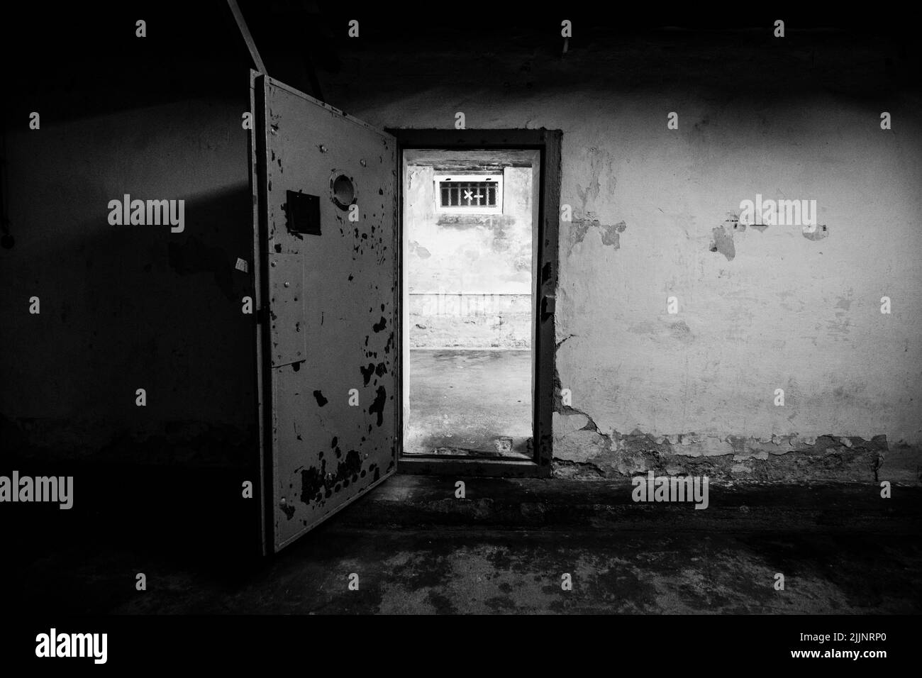 A grayscale shot from an abandoned old room with white walls and an ...