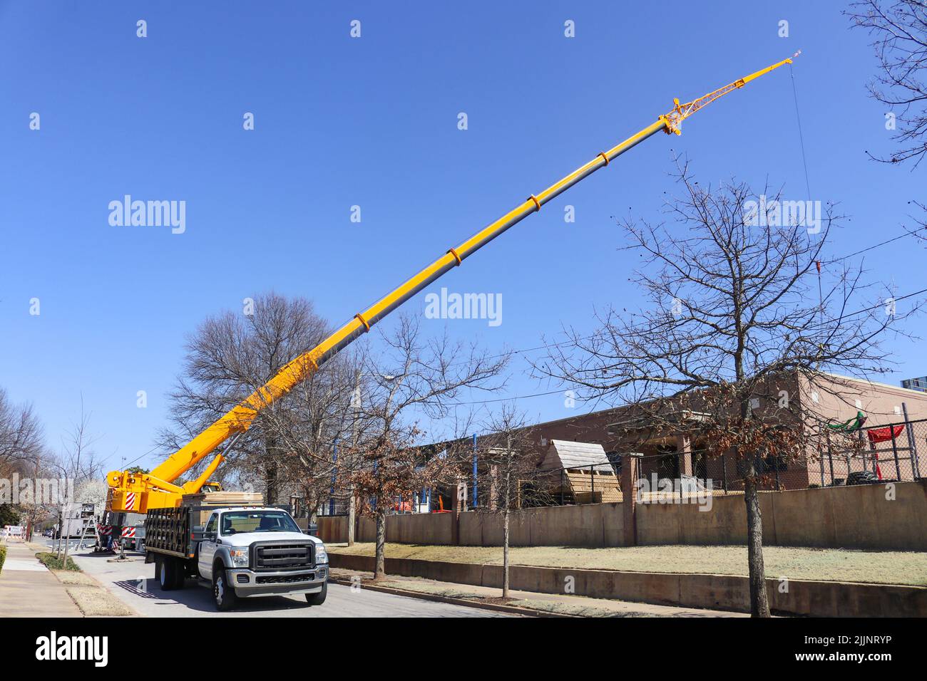 Giant yellow crane set up on blocked urban street stretching up above ...