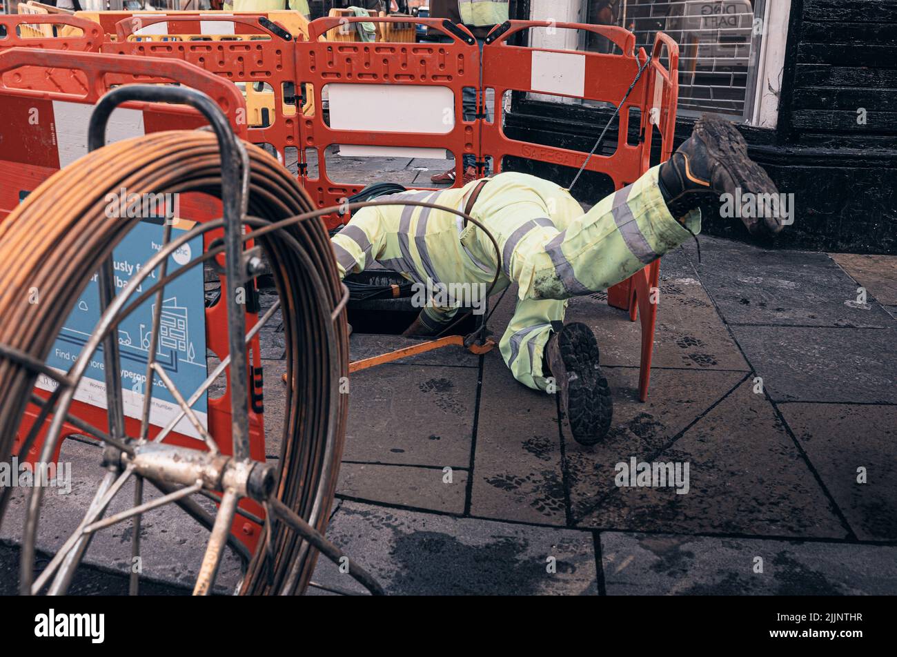 A manual worker wearing uniform fixing water pipes in manhole Stock ...