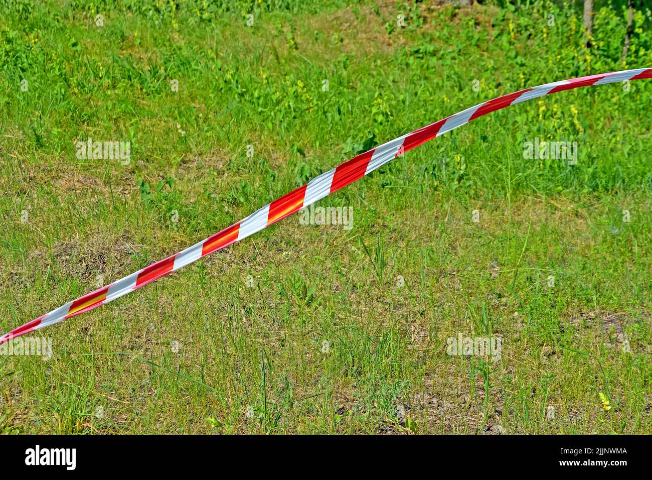 red security warning ribbon on green grass, windy environment diversity ...