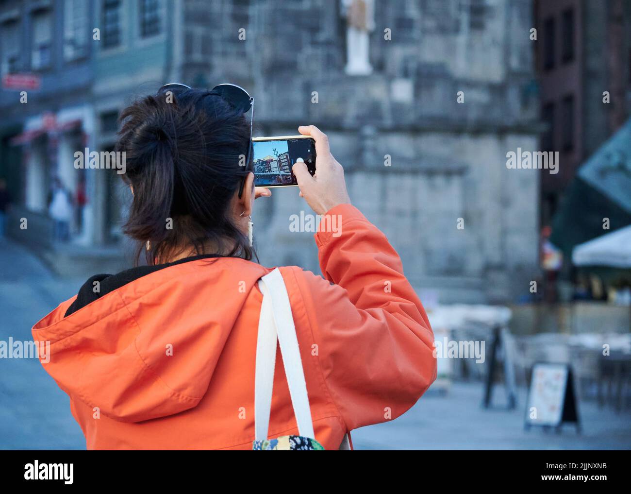 A rear view of a Spanish young woman taking pictures of sights in Porto ...