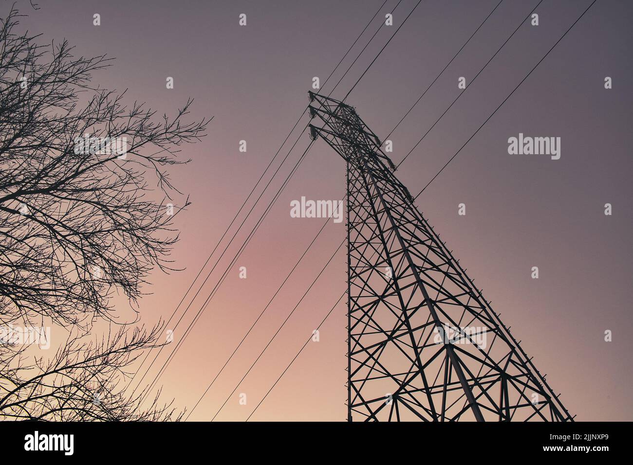 A low angle of electrical power tower under a beautiful sunset sky in ...
