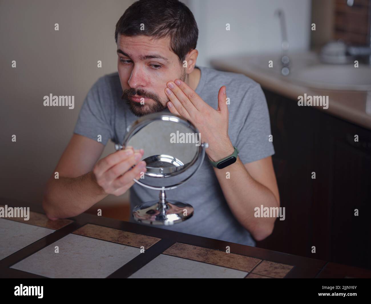 guy checking his skin. Young man looking in mirror touches face with ...