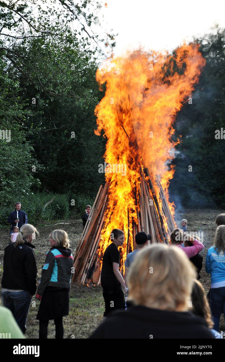 A vertical shot of people next to the bonfire celebrating St John's Eve ...