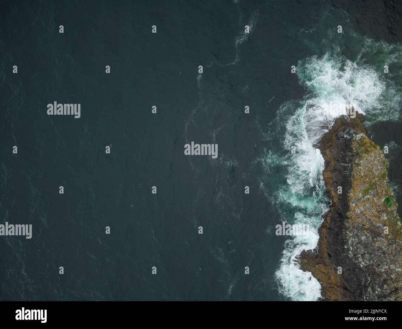 Shooting from a drone. Dark turquoise ocean surface. Foamy waves crash ...