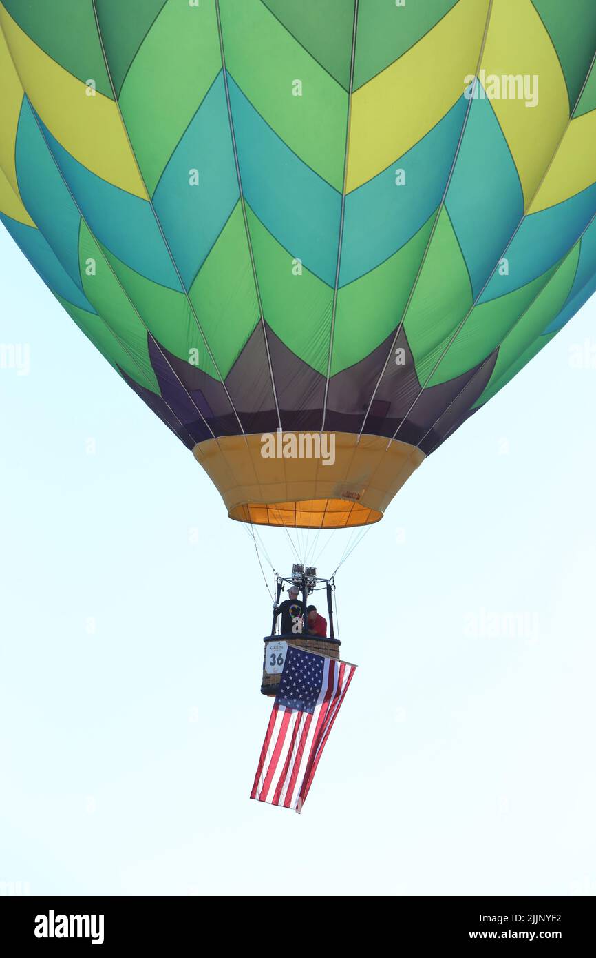 A vertical shot of an air balloon waving the American flag in the air ...