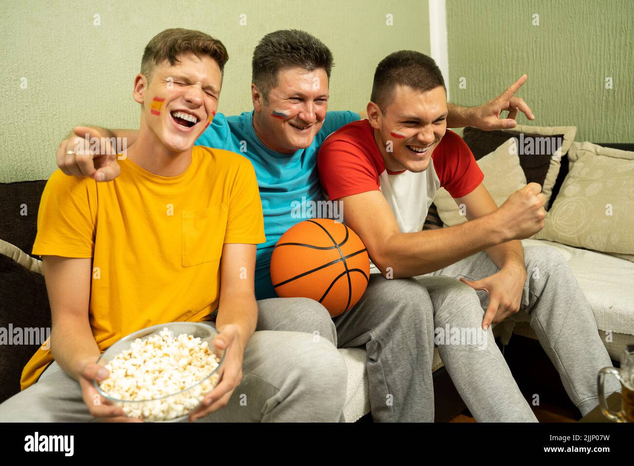 Three male basketball fans watching the game and celebrating victory ...