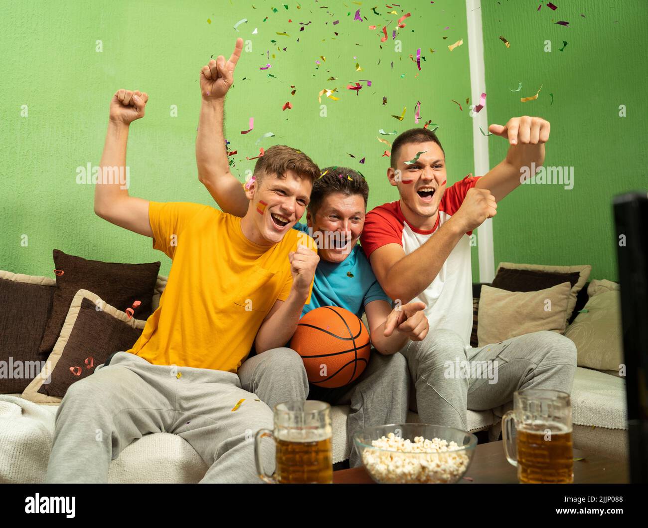 Three male basketball fans watching the game and celebrating victory ...