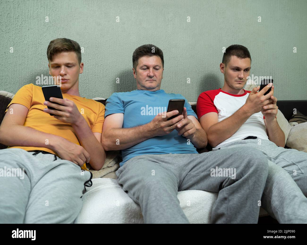 Three young males using their mobile phones Stock Photo - Alamy