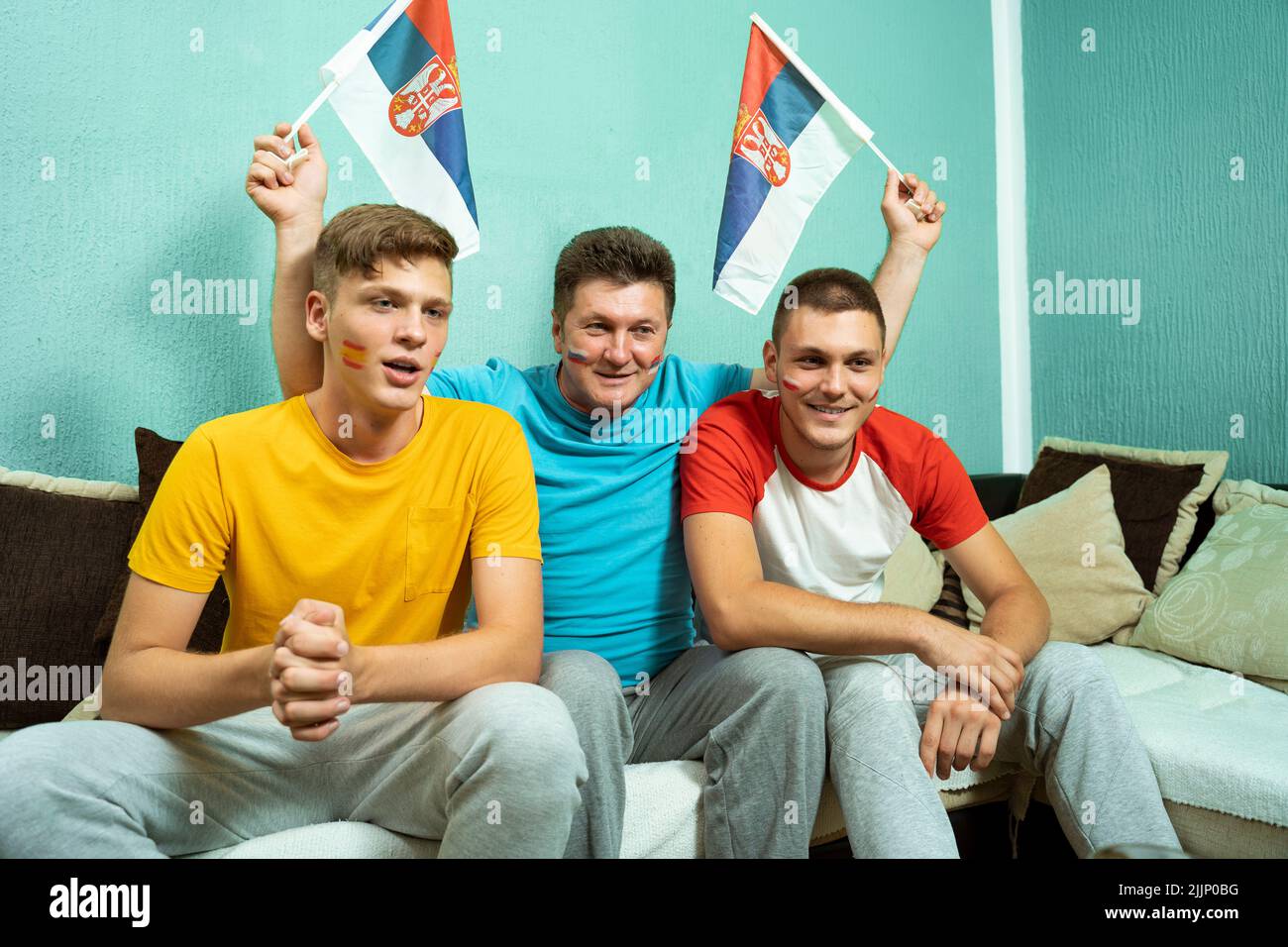Three male basketball fans watching the game and cheering on Serbia ...