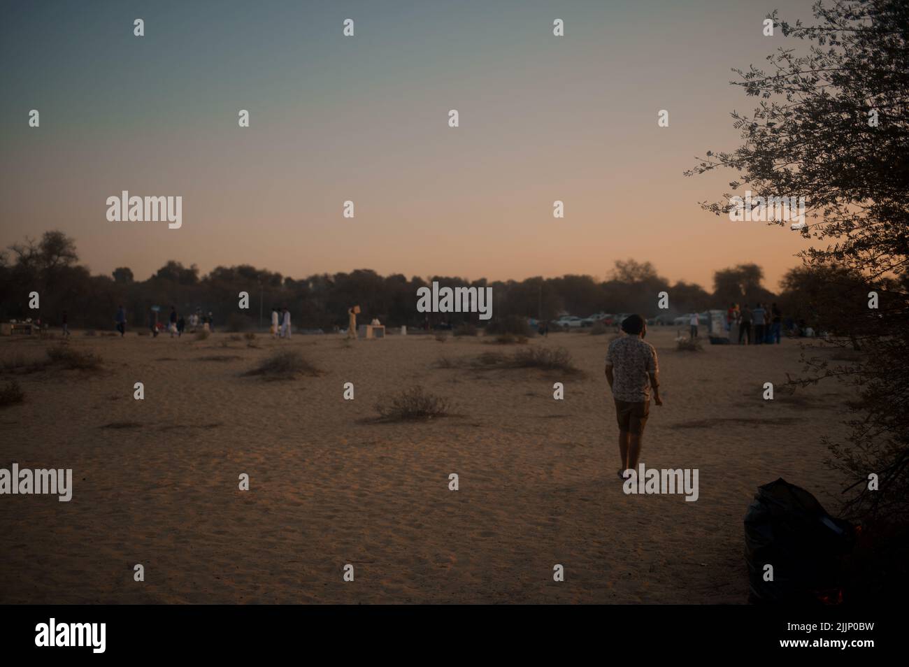 Many people standing on a sand during the sunset Stock Photo - Alamy