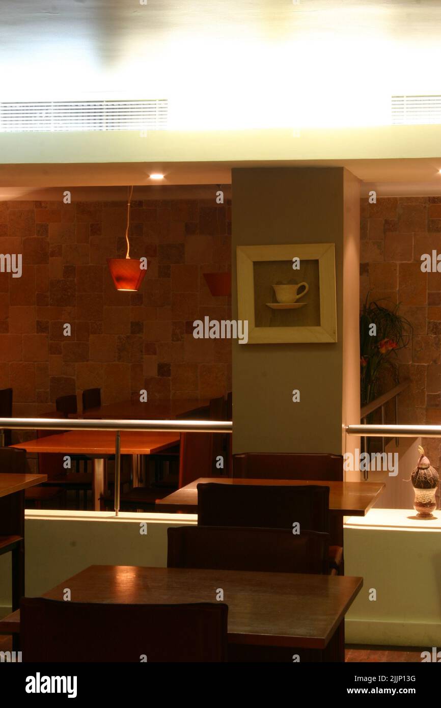 A vertical shot of the interior of a cafe with wooden tables and chairs ...