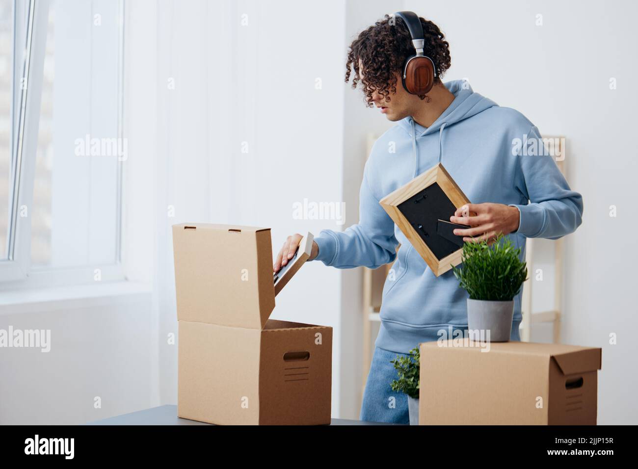 portrait of a man cardboard boxes in the room unpacking in headphones ...