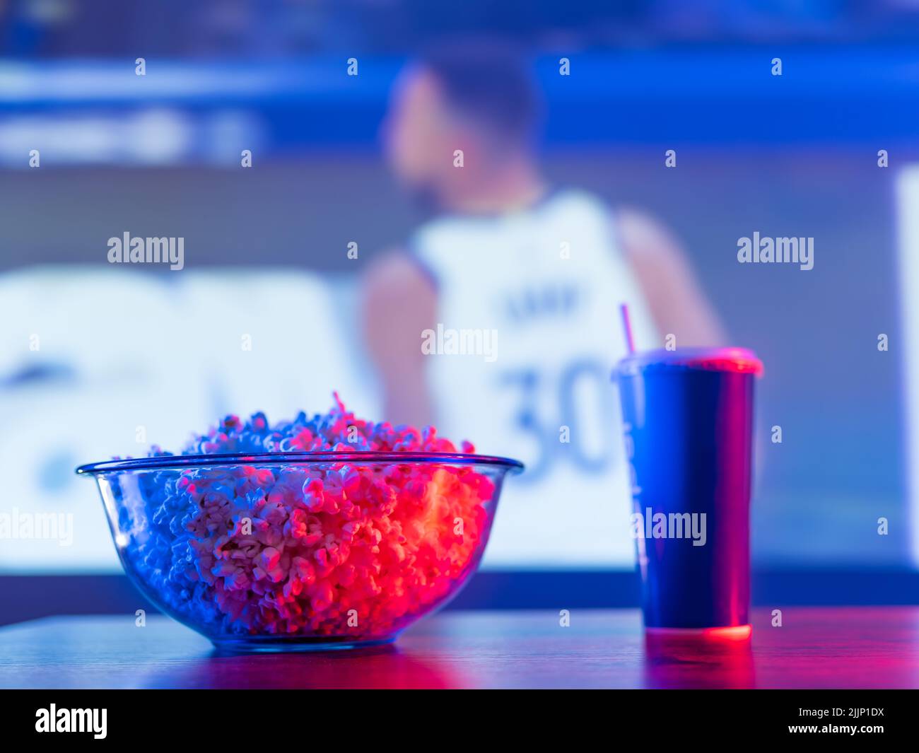 Basketball match on the big TV screen. On the table is a glass bowl ...