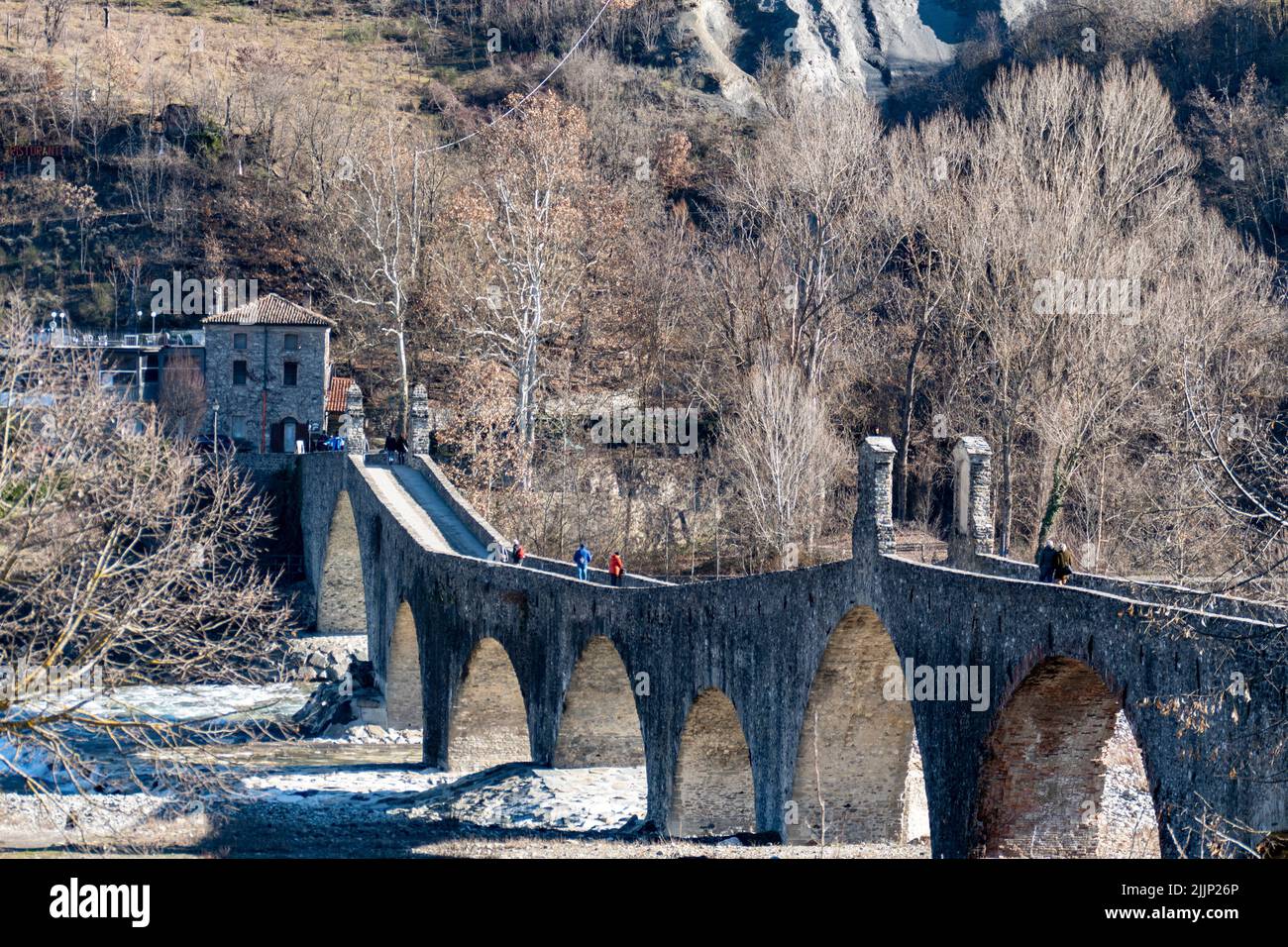 The Ponte Gobbo (Hunchback Bridge) in Bobbio, Italy with dry trees ...